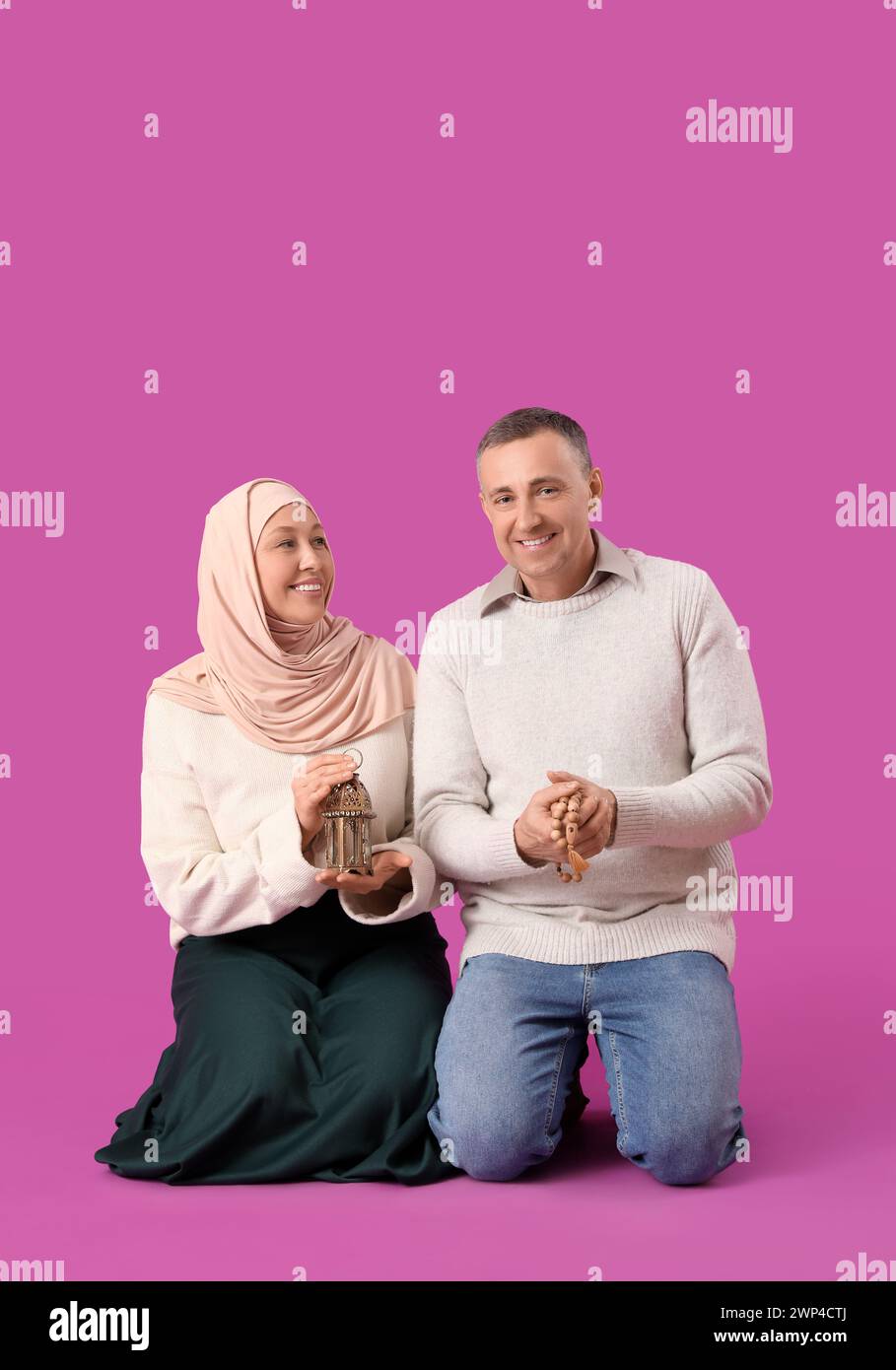 Happy Muslim couple with prayer beads and fanoos on pink background ...
