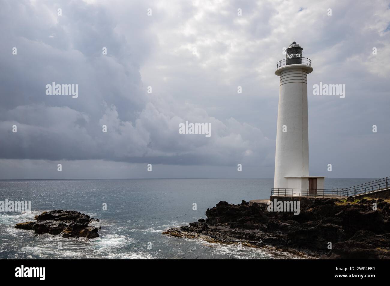 White lighthouse on a steep coast. Dramatic clouds with a view of the ...