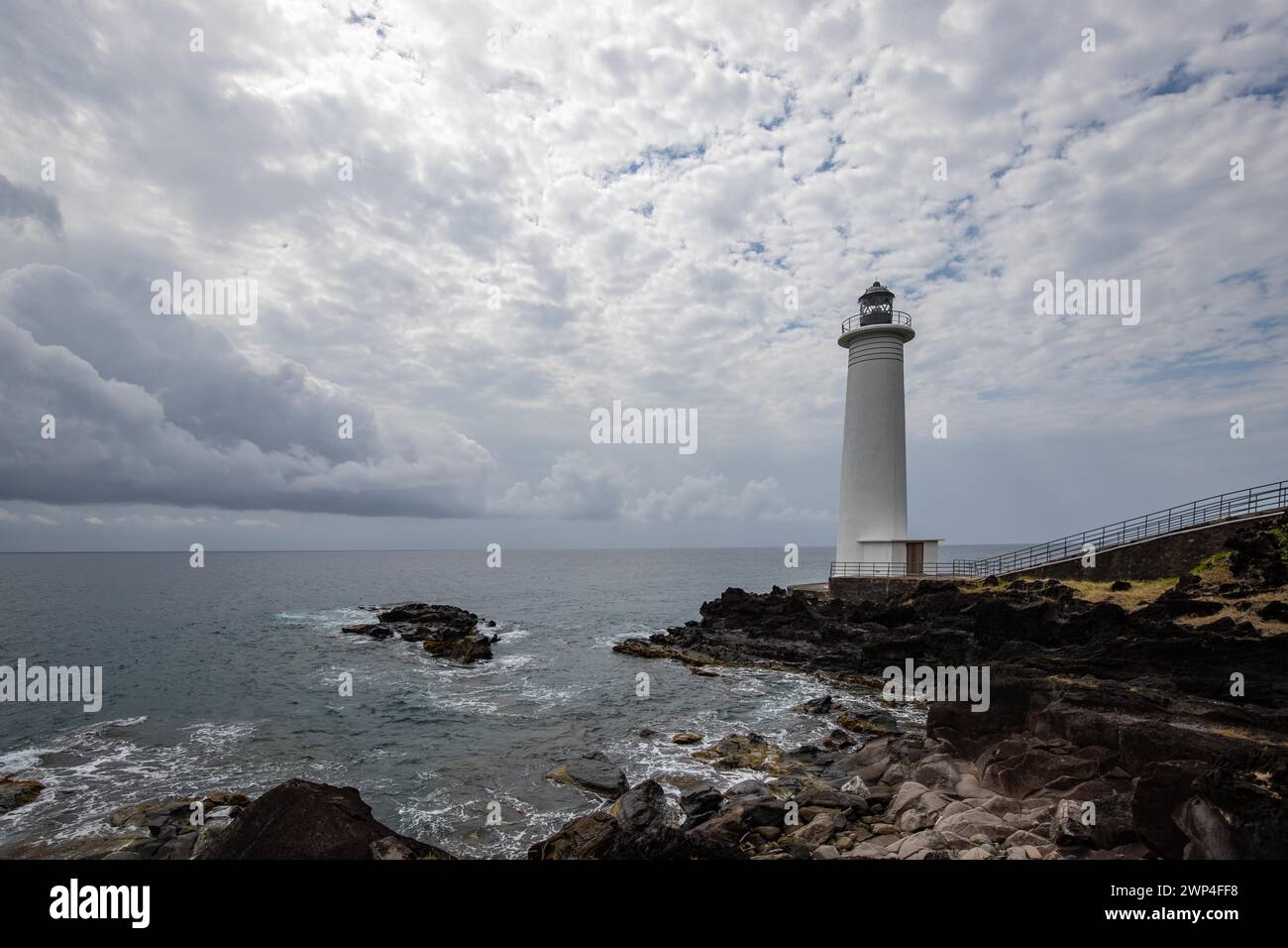 White lighthouse on a steep coast. Dramatic clouds with a view of the ...