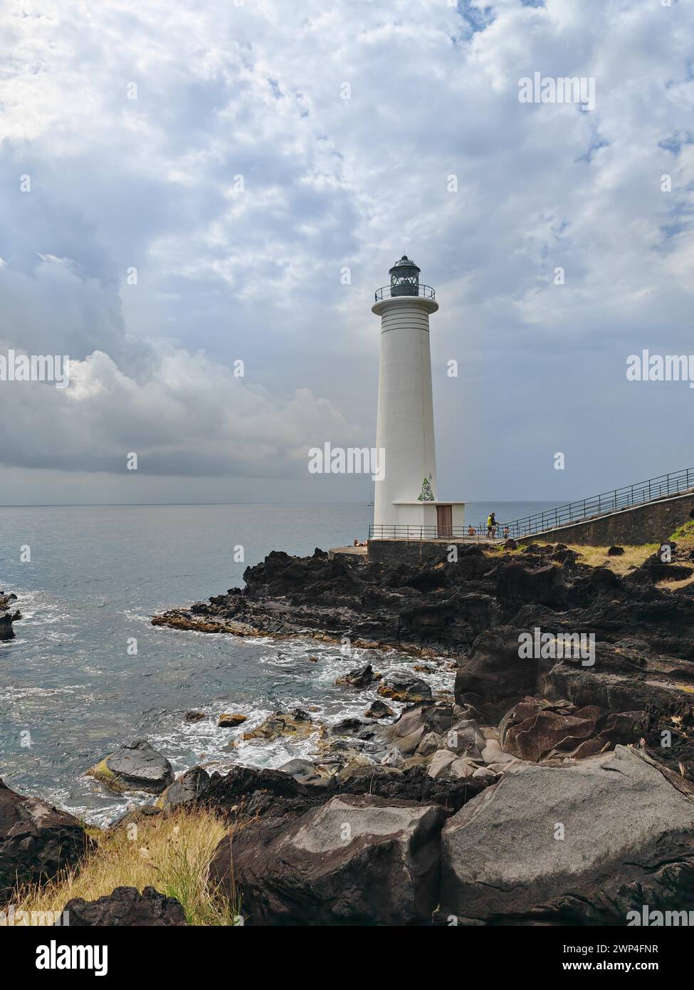 White lighthouse on a steep coast. Dramatic clouds with a view of the ...