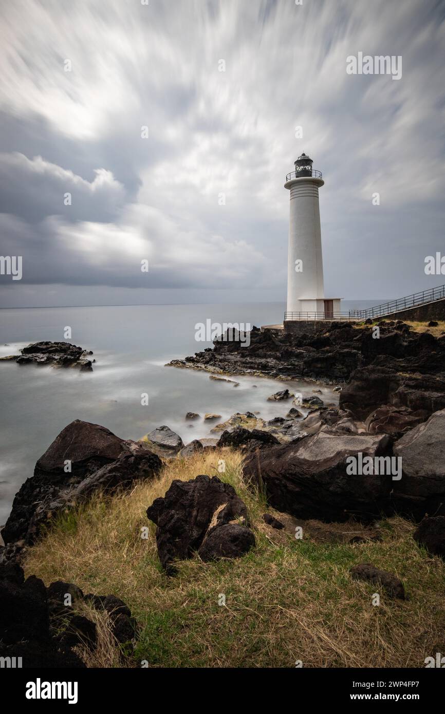 White lighthouse on a steep coast. Dramatic clouds with a view of the ...
