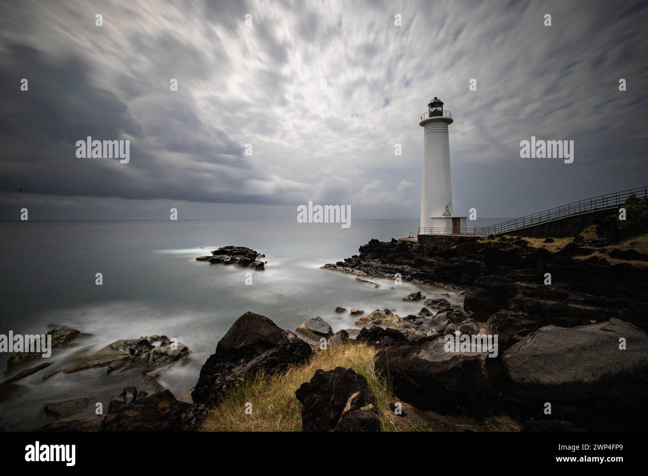 White lighthouse on a steep coast. Dramatic clouds with a view of the ...