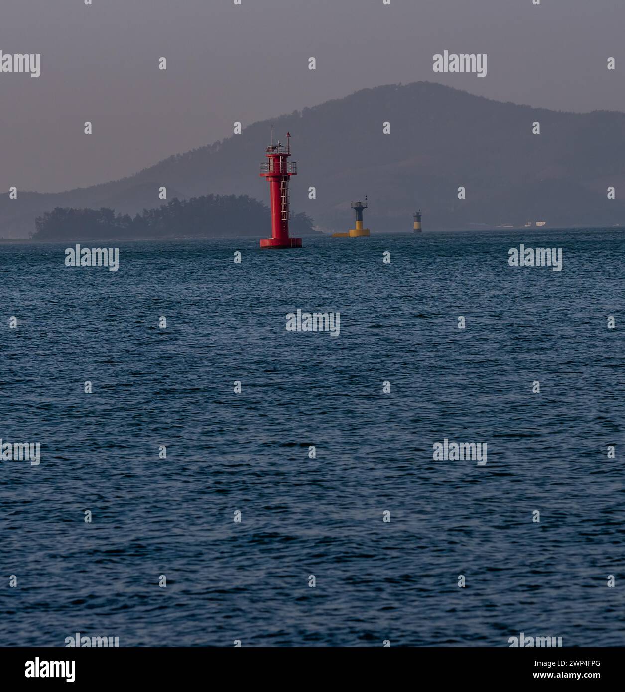 Three small lighthouses in a harbor with small mountains shrouded in ...