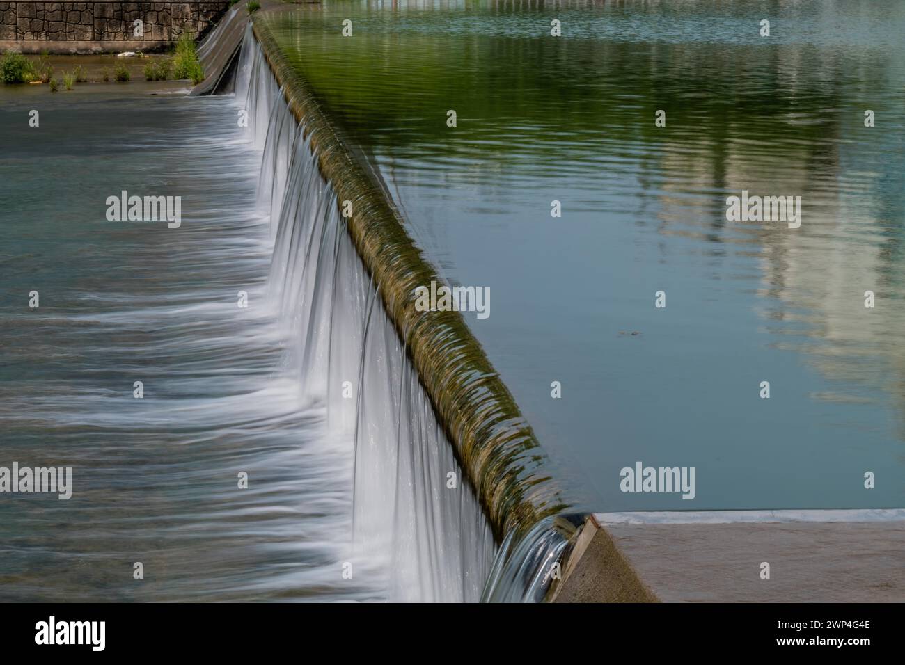 Water cascades down a spillway, creating a smooth waterfall effect, in ...