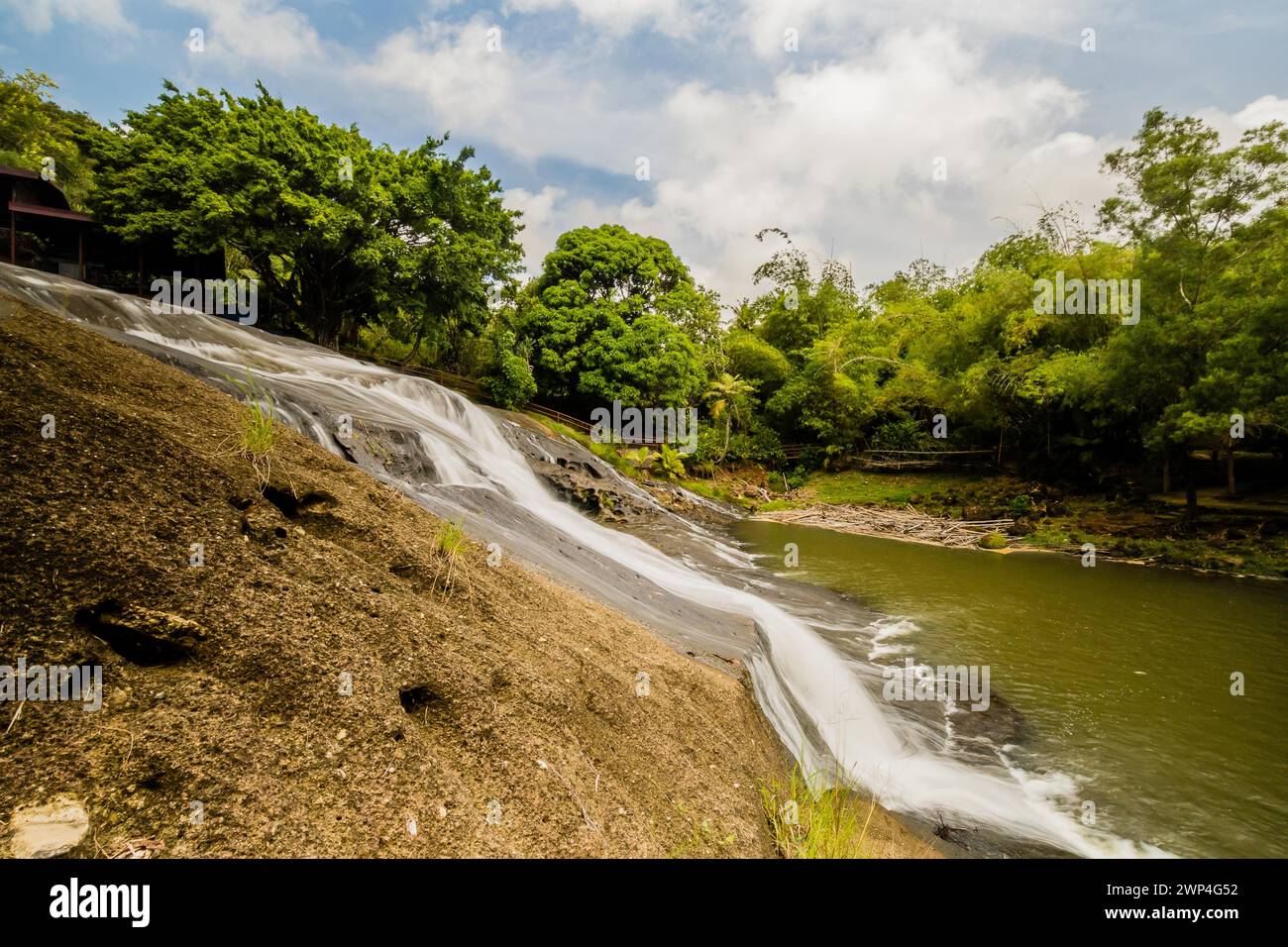 Side view of a waterfall cascading down a cliff into the basin below ...