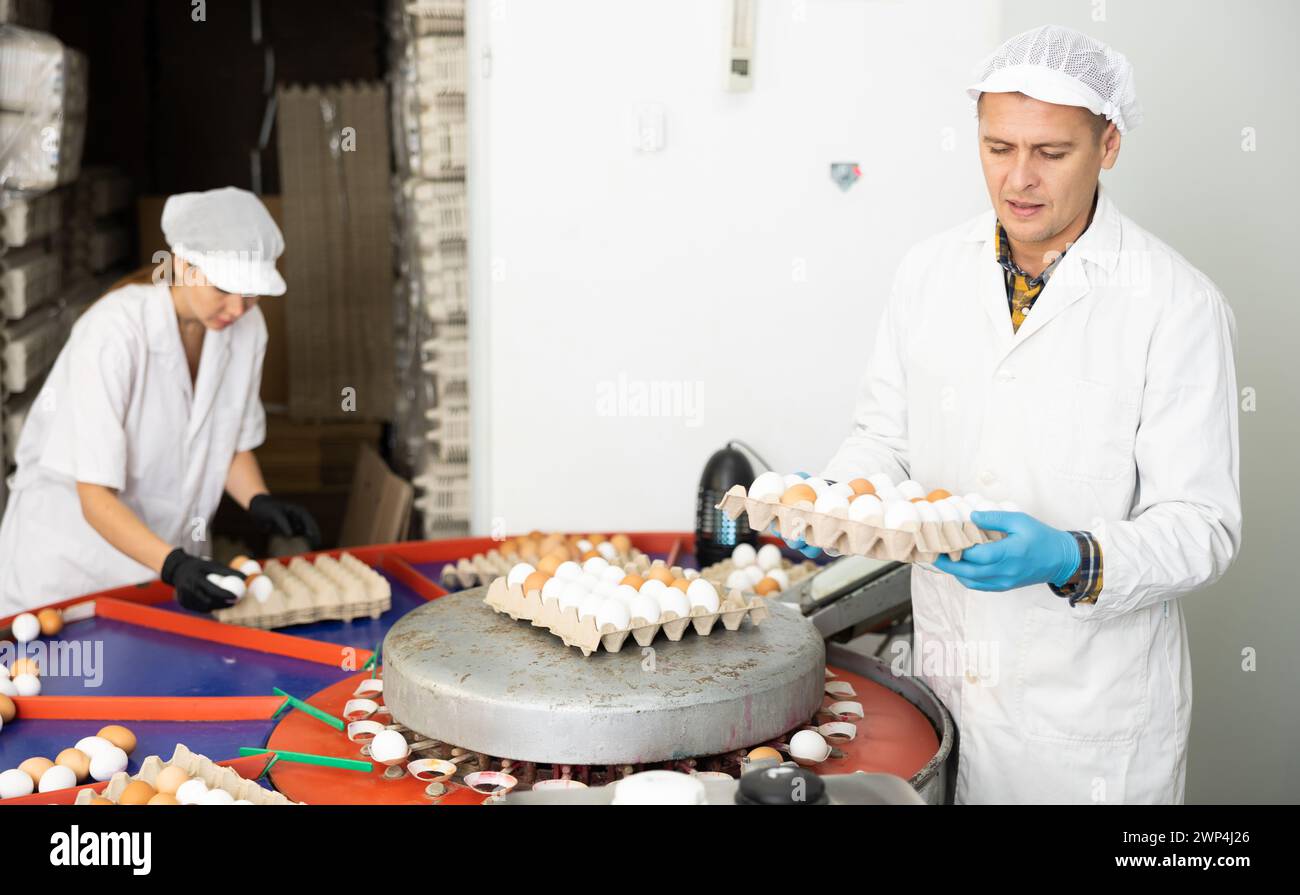 Young European male and female farmers in uniform sorting and labeling ...