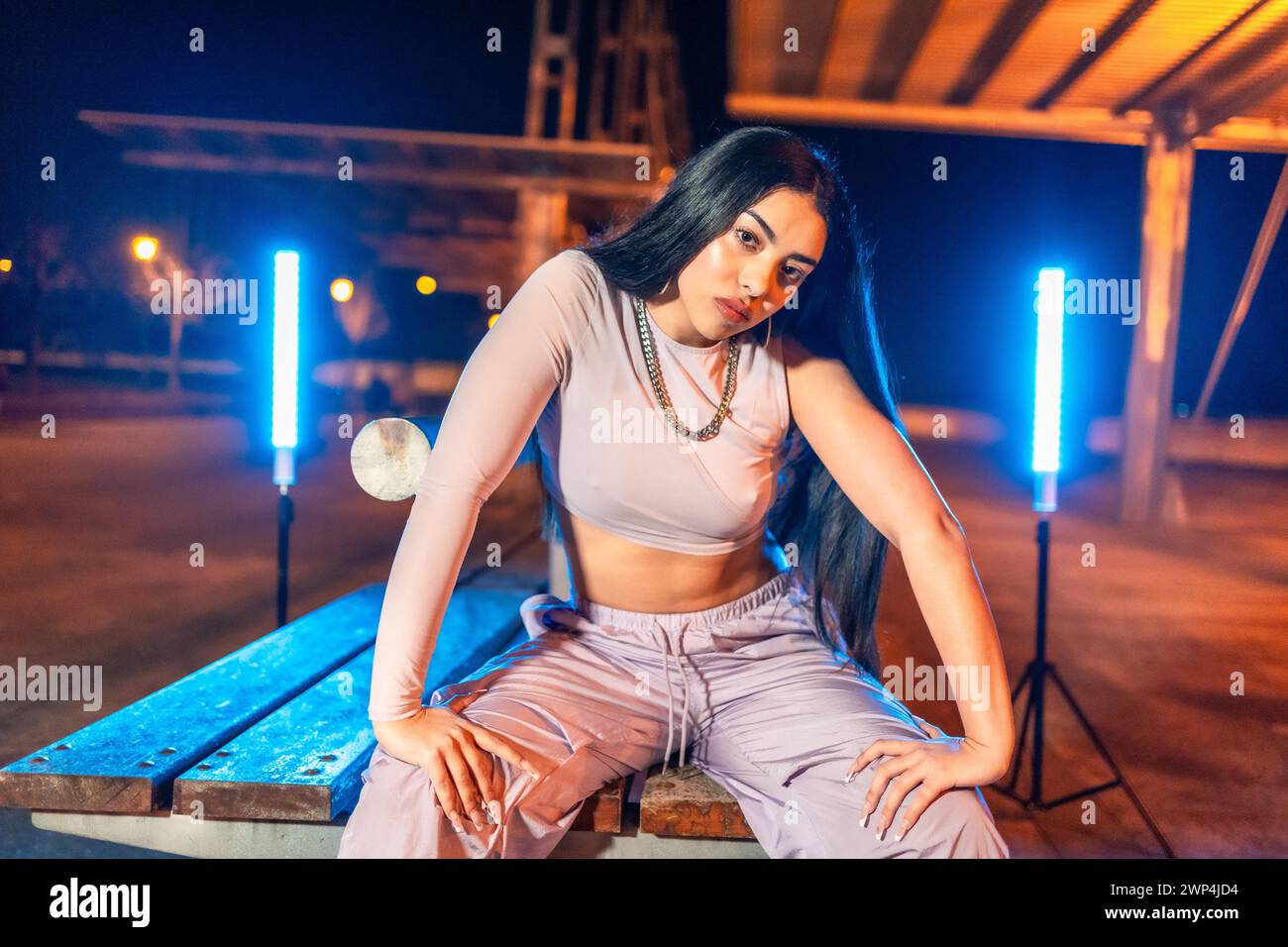 Portrait of a trap dancer sitting confident in an urban park looking at ...