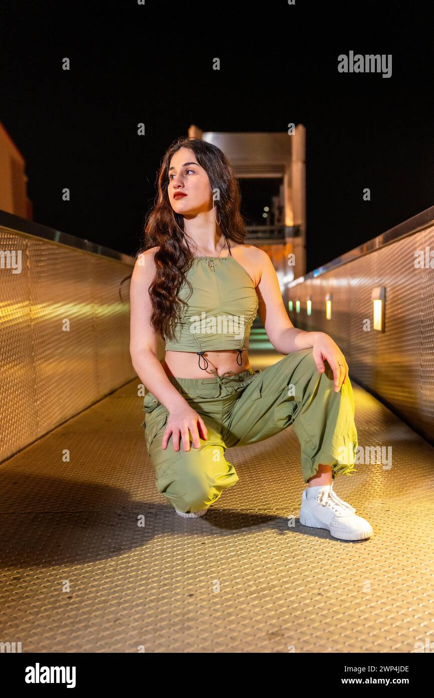 Vertical portrait of a freestyle dancer kneeling posing outdoors at ...