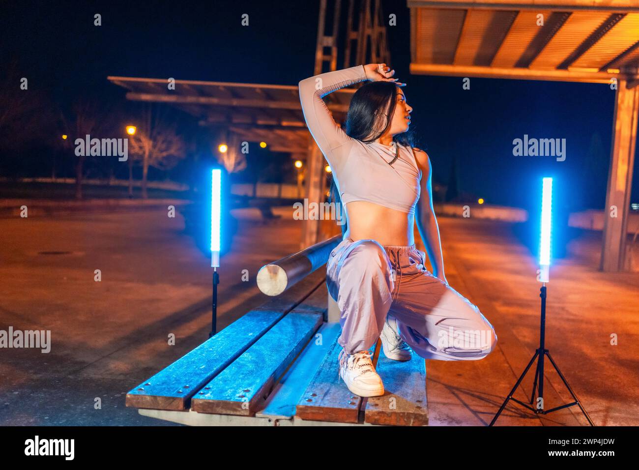 Sensual cool rap artist crouching and posing in a park at night ...