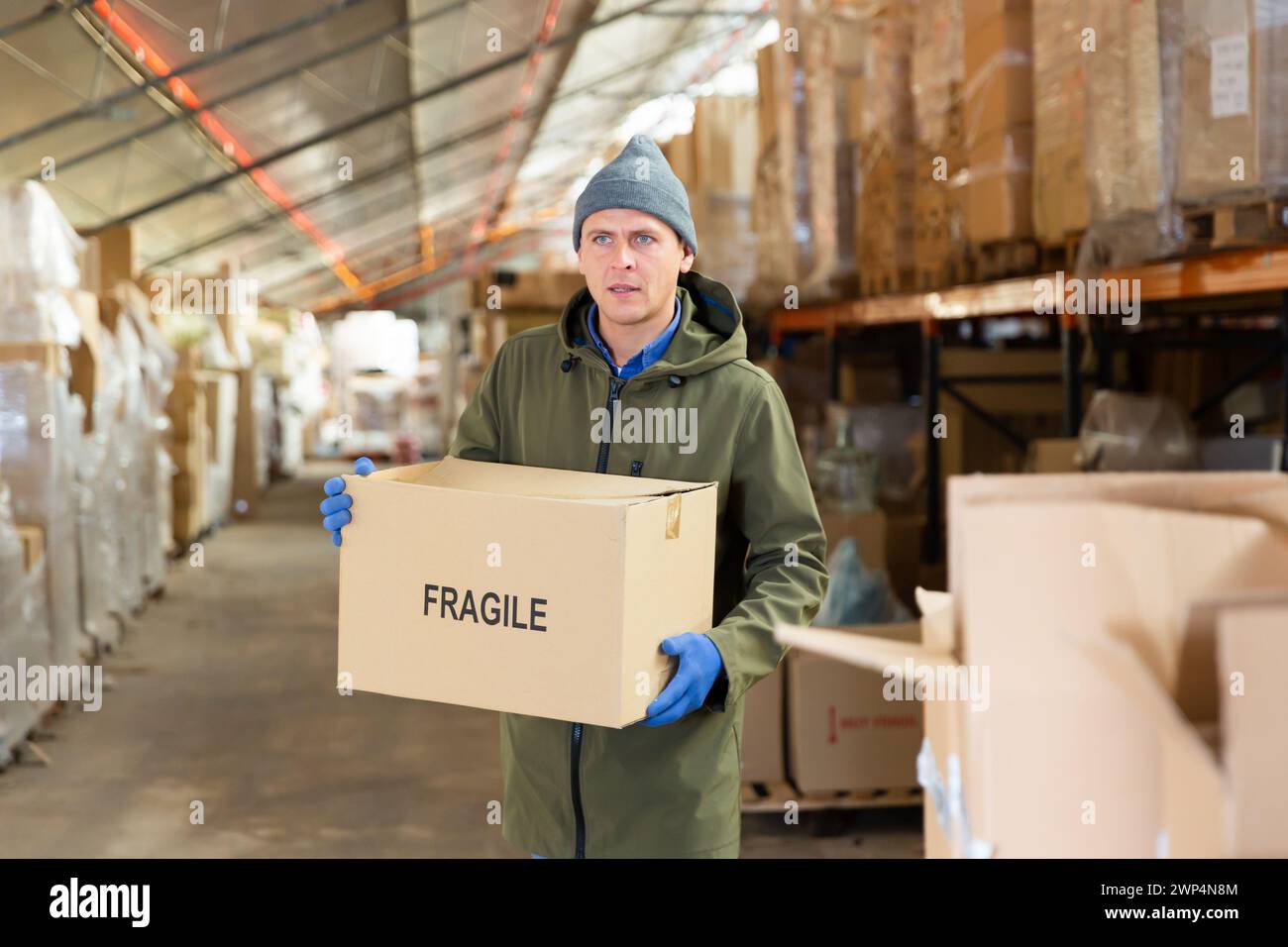 Warehouse worker carrying large box of goods in arehouse Stock Photo ...