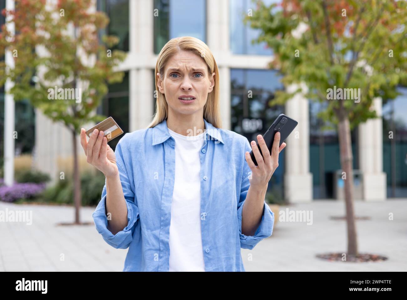 Blue eyed woman standing next to shopping mall with debit card and ...