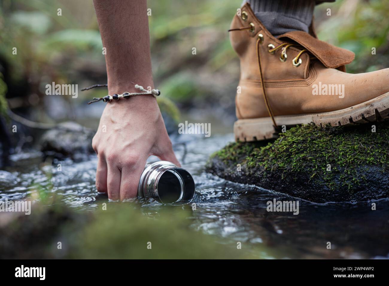 Close-up of hand and foot with metal container collecting water from ...