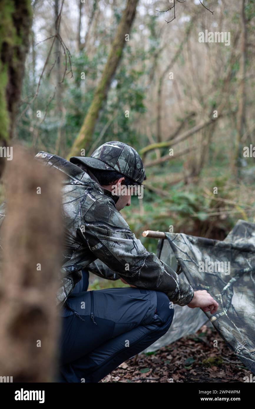 A man dressed in camouflage clothing is seen in action, constructing an ...