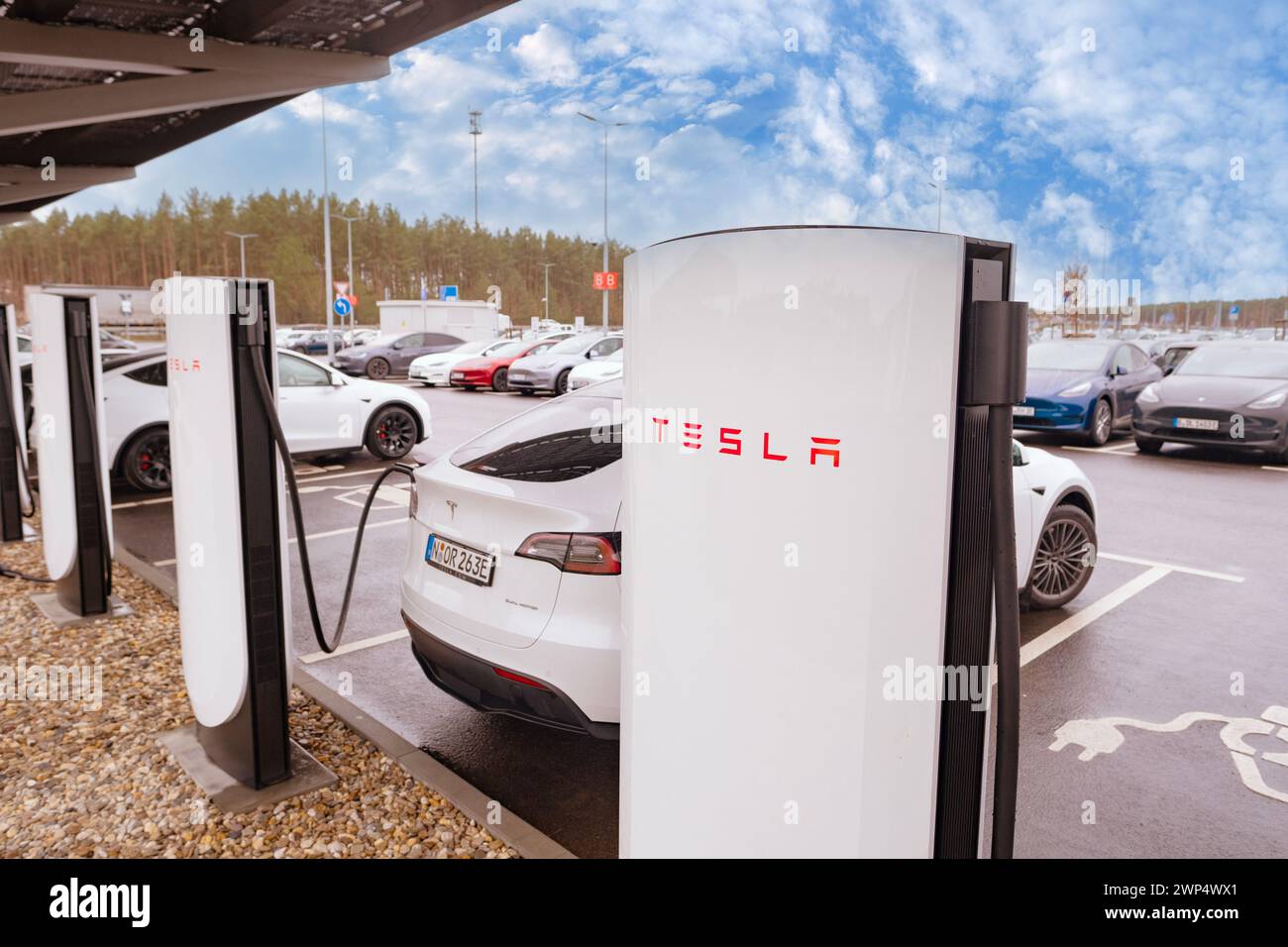white Tesla electric car replenishes battery at charging station ...