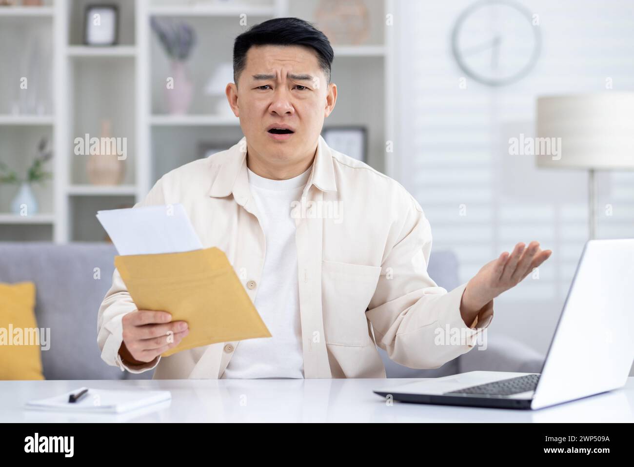 Worried korean male opening paper envelop with documents and sitting by ...
