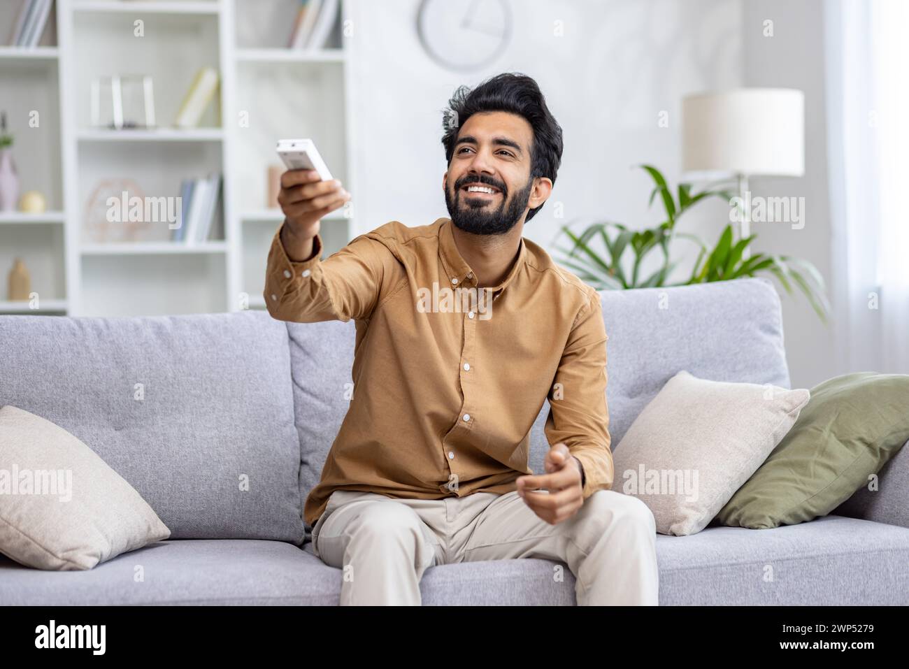 Relaxed middle eastern man chilling on sofa while switching air ...