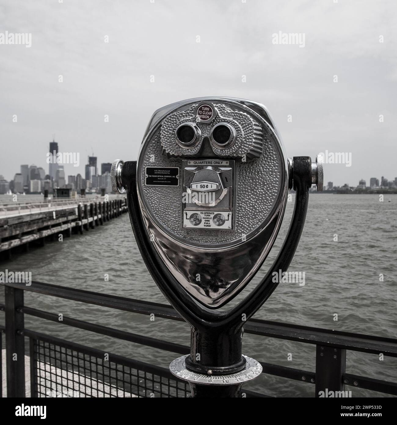 A coin-operated telescope pointed out towards the water, with the ...