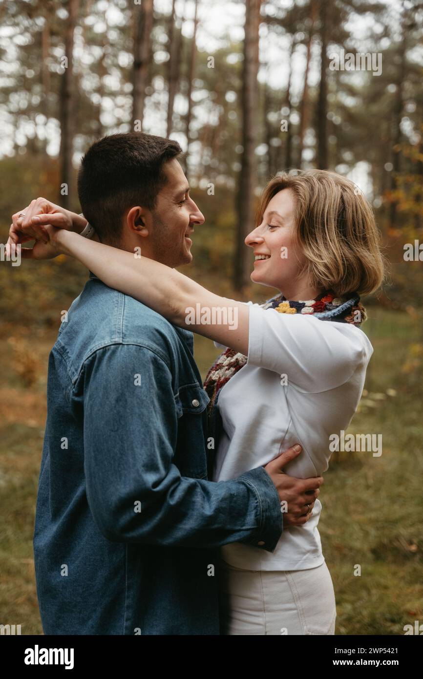 Happy man and a woman are embracing each other in the forest in autumn ...