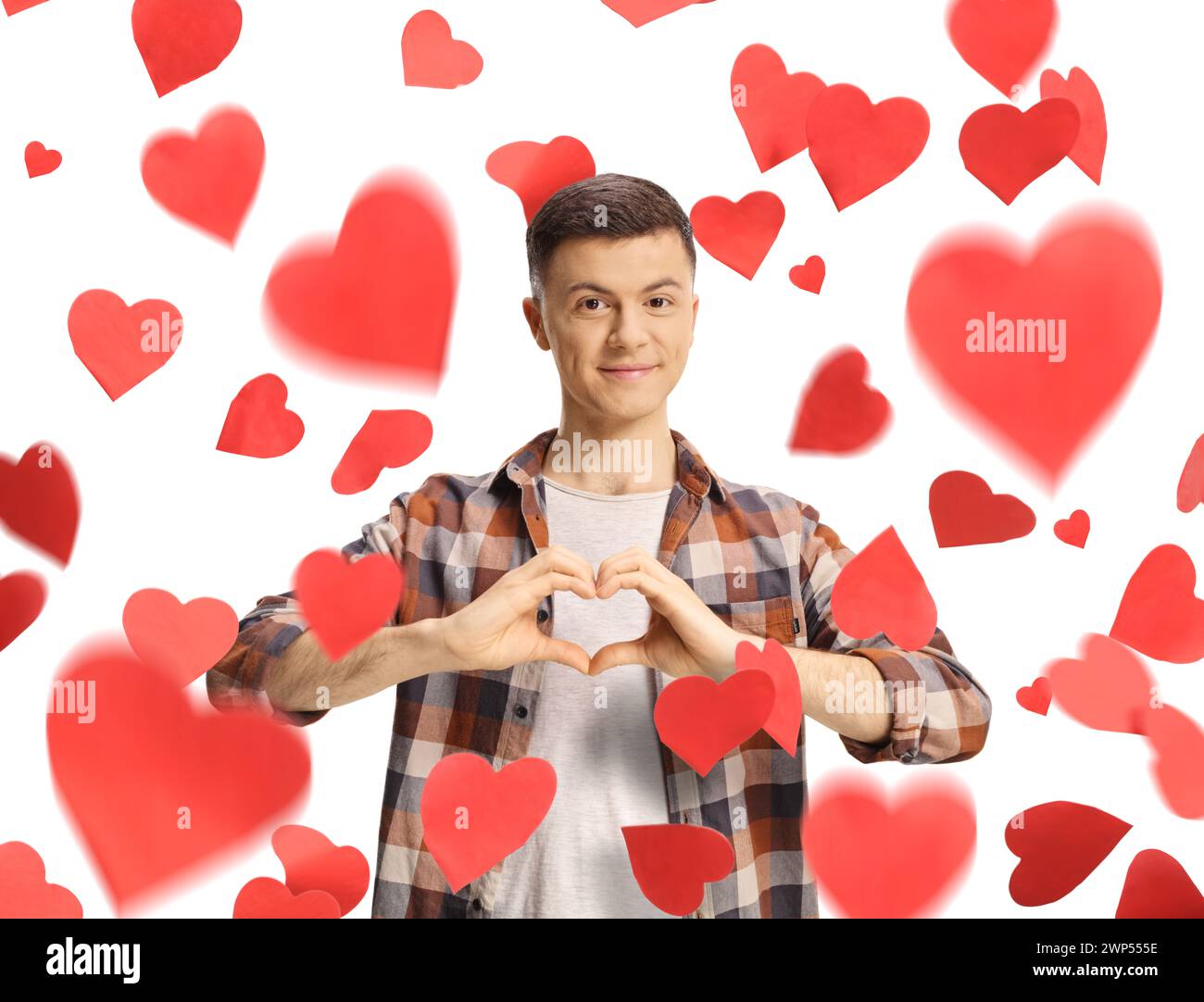 Young casual man under falling hearts gesturing a heart symbol with ...