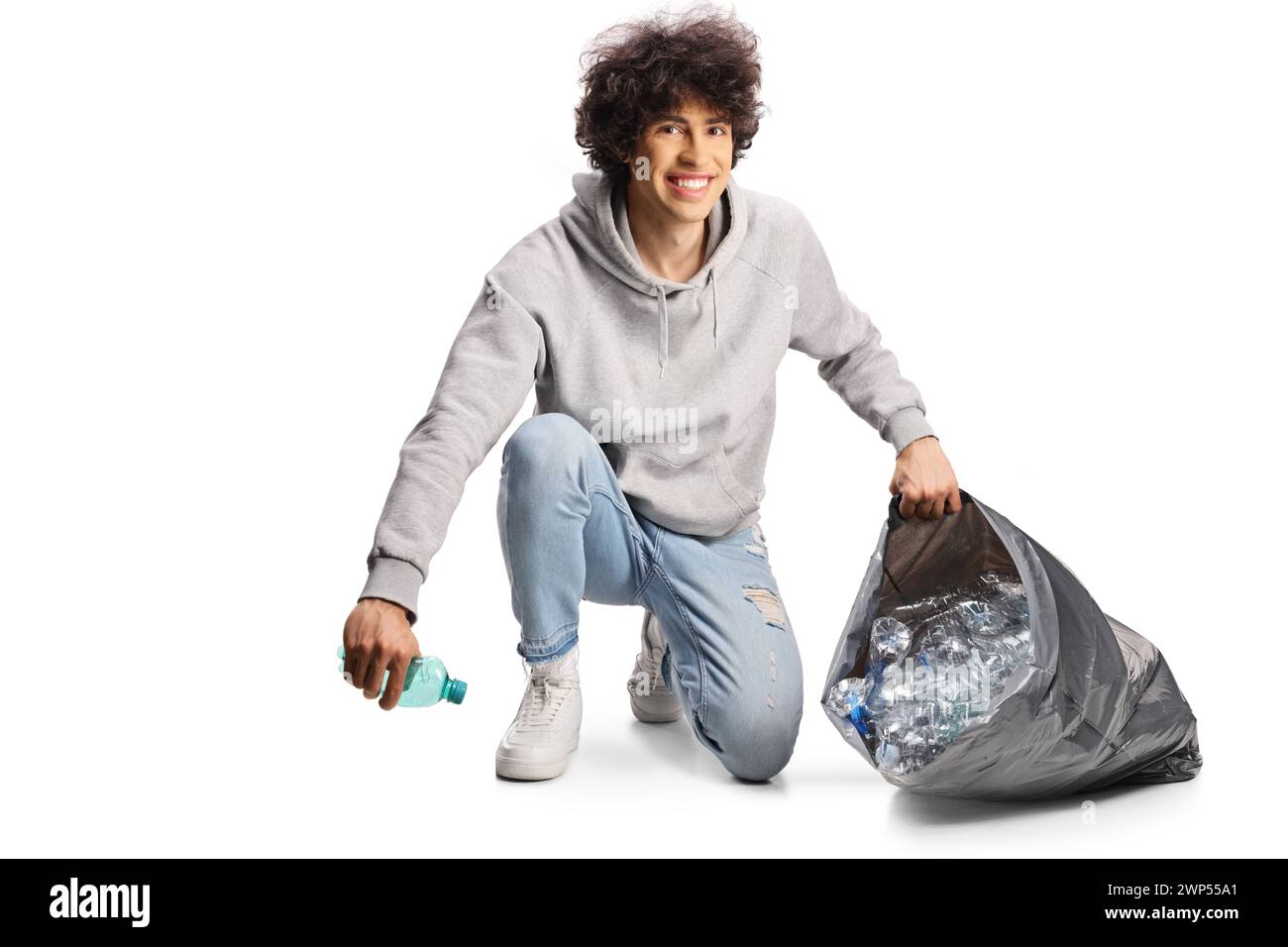 Young man collecting plastic bottles in a black waste bag isolated on ...