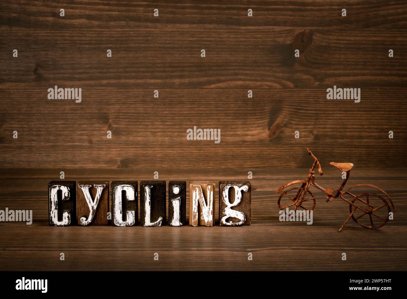 CYCLING. Text from alphabet blocks and rusty miniature bicycle on wood ...