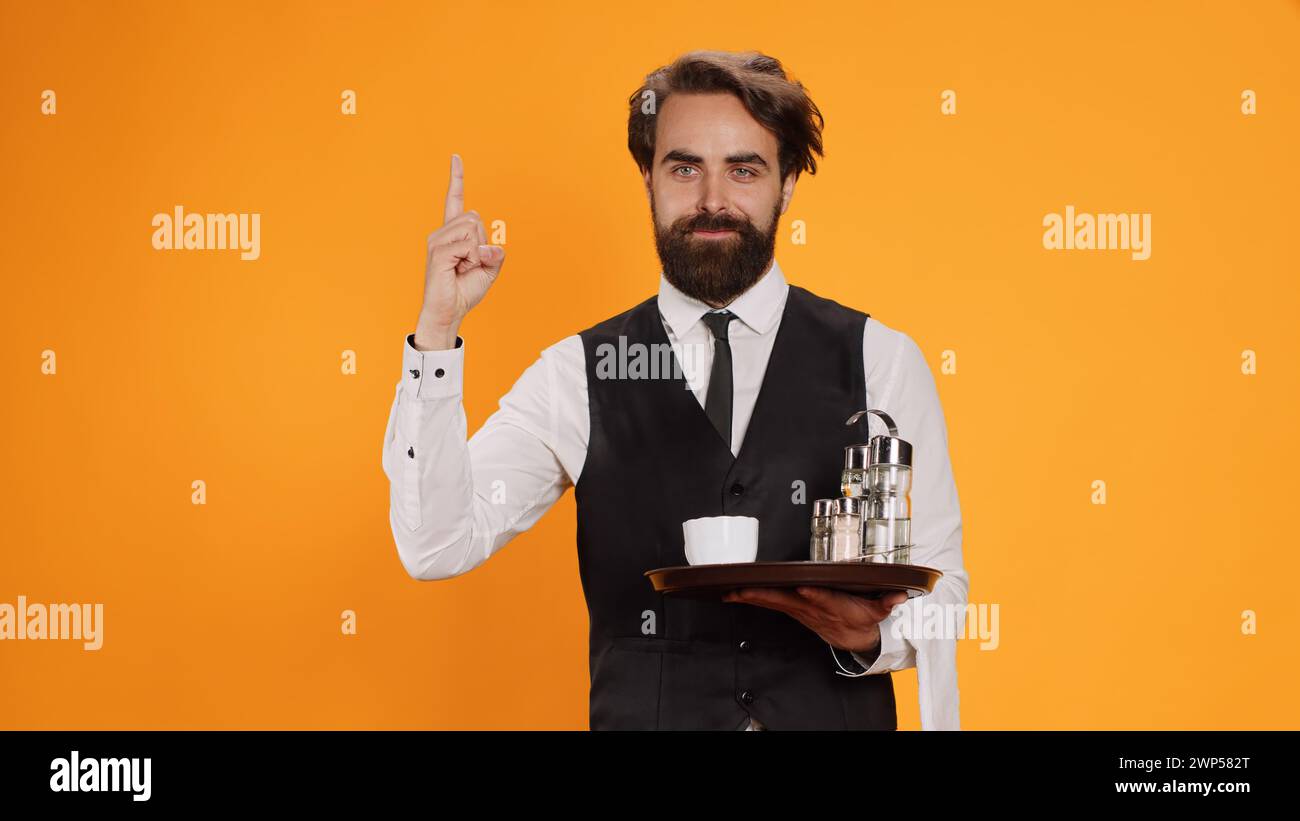 Elegant butler having new idea on camera, raising index finger and ...