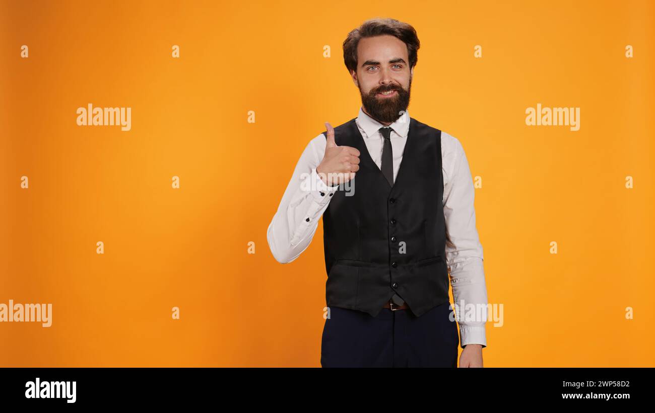 Trendy valet raises thumbs up gesture in studio to symbolize ...
