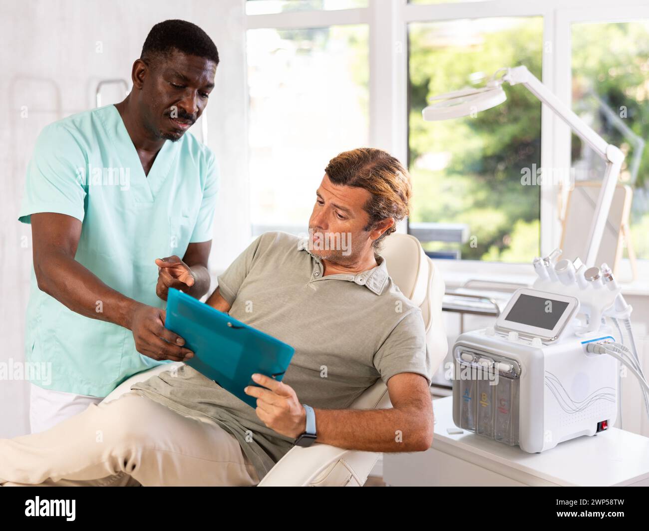 Male patient signing informed consent form during consultation with ...
