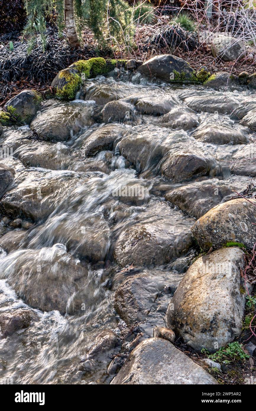 Garden stone waterfall feature in low winter light. Cascading rock ...