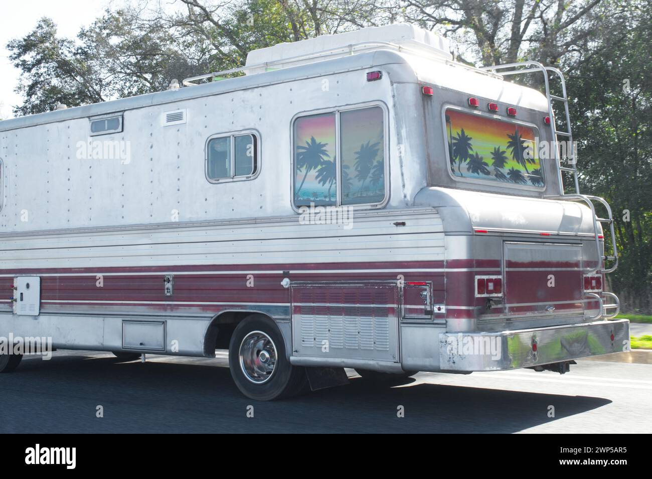 Large older late model vintage RV recreational vehicle driving down a ...