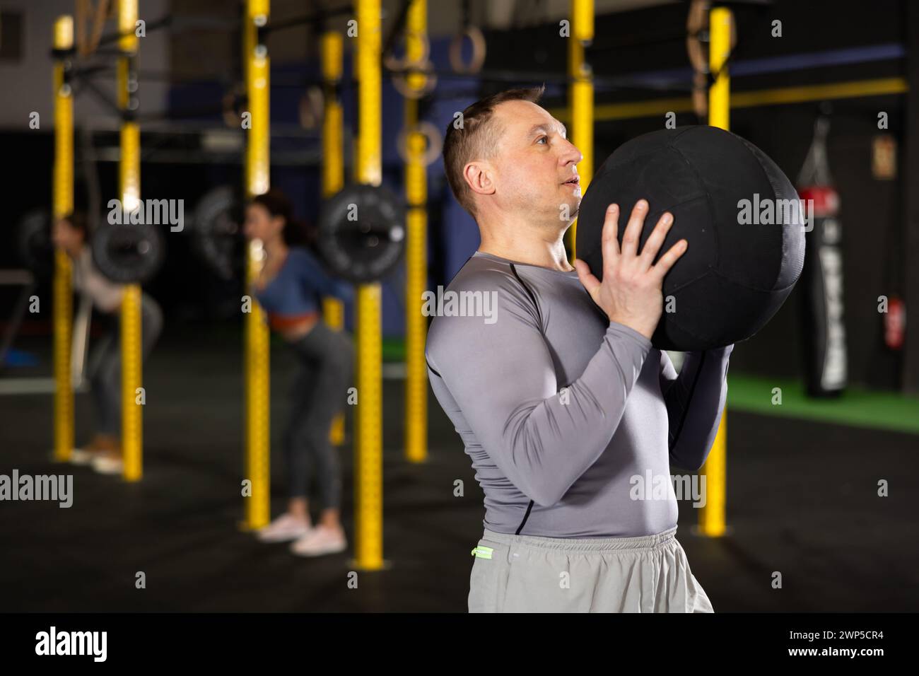 Middle-aged man working out with medicine ball in gym Stock Photo - Alamy