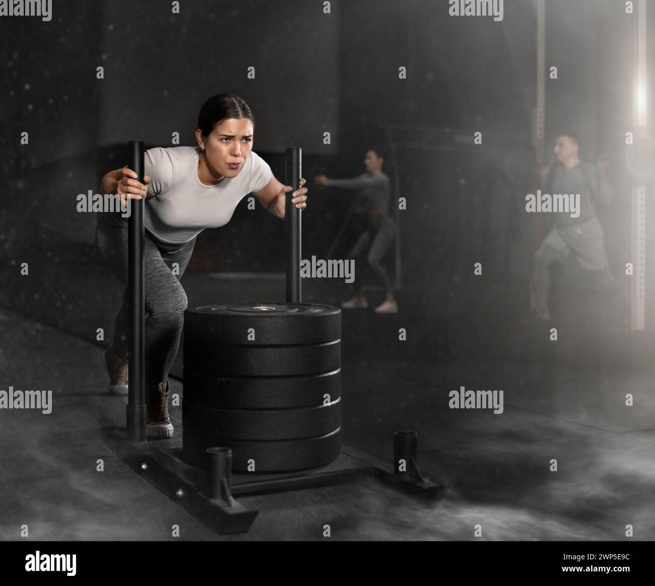 Young woman during grueling workout with element of push and pull ...
