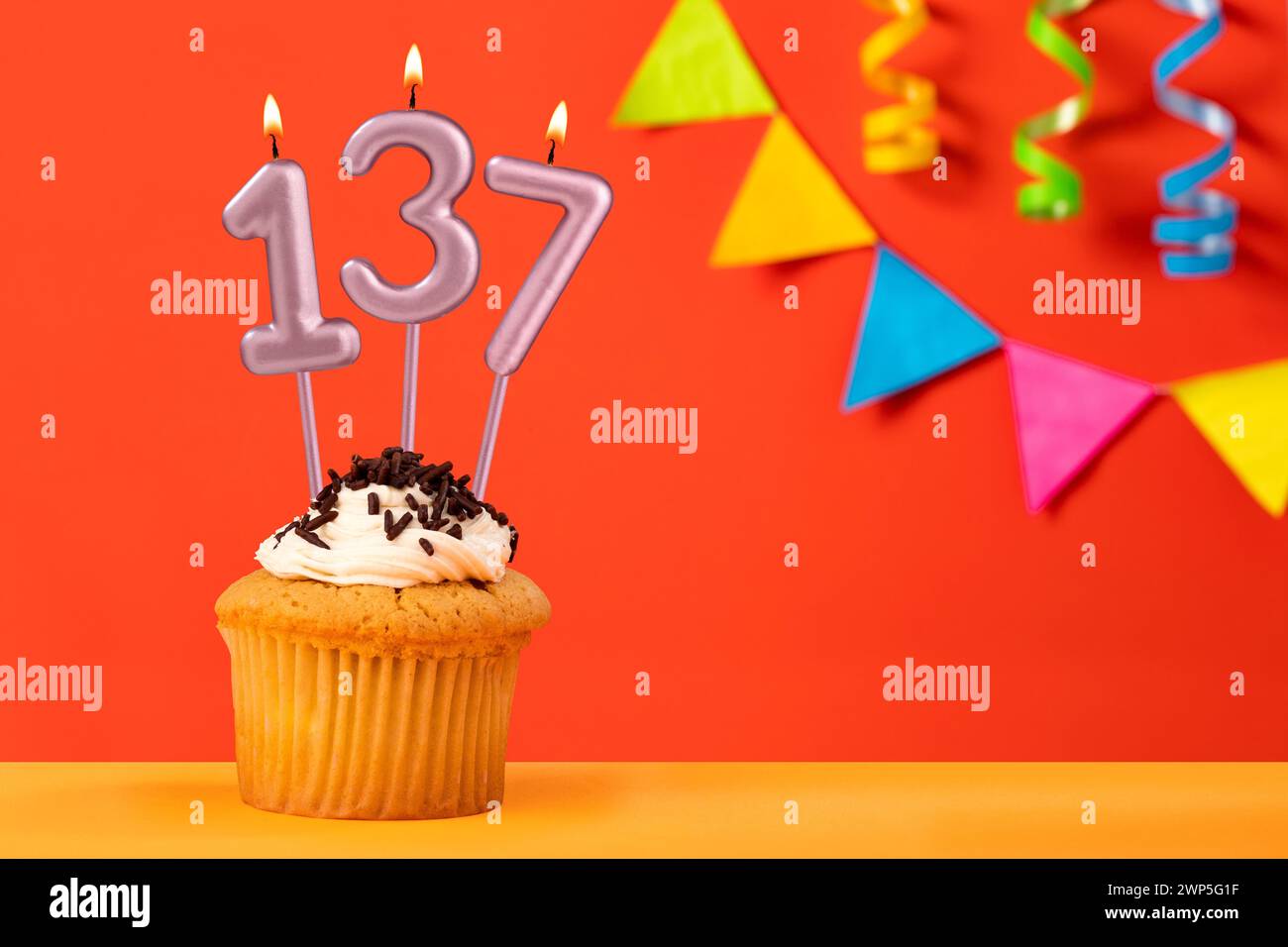 Birthday cupcake with number 137 candle - Sparkling orange background ...