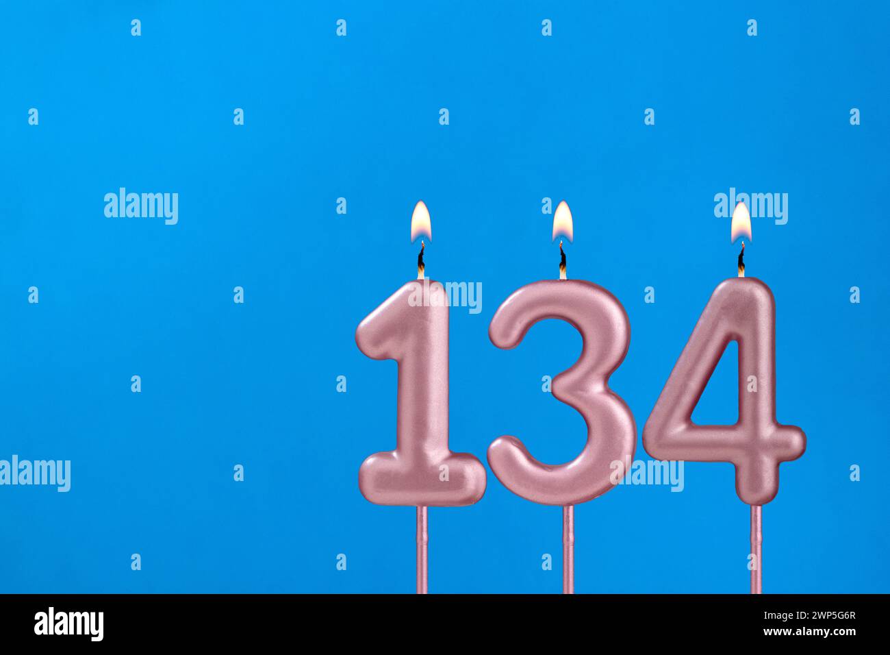 Number 134 - Burning anniversary candle on blue foamy background Stock ...