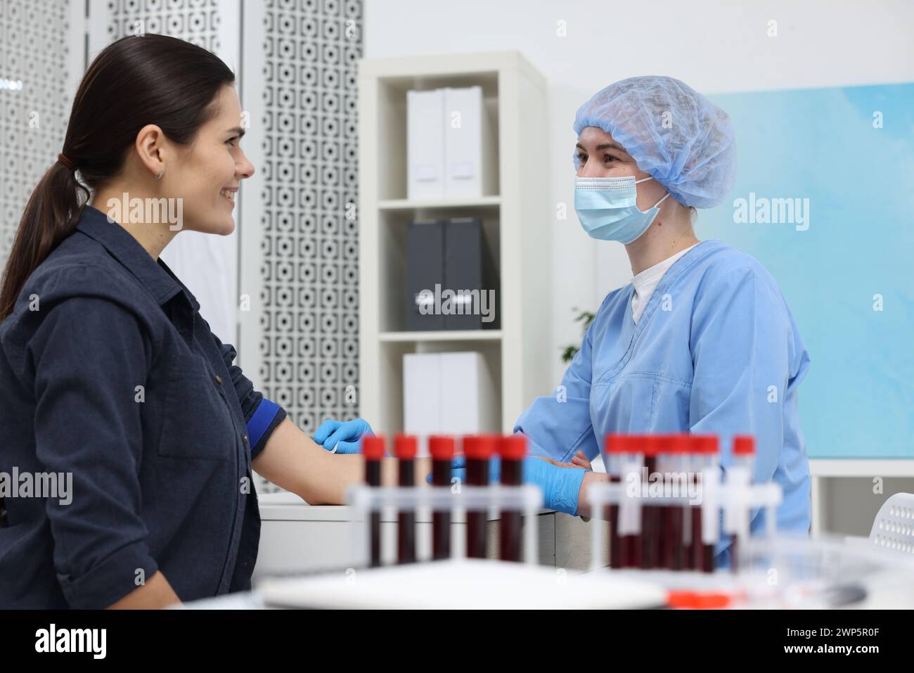 Laboratory testing. Doctor taking blood sample from patient at table in ...