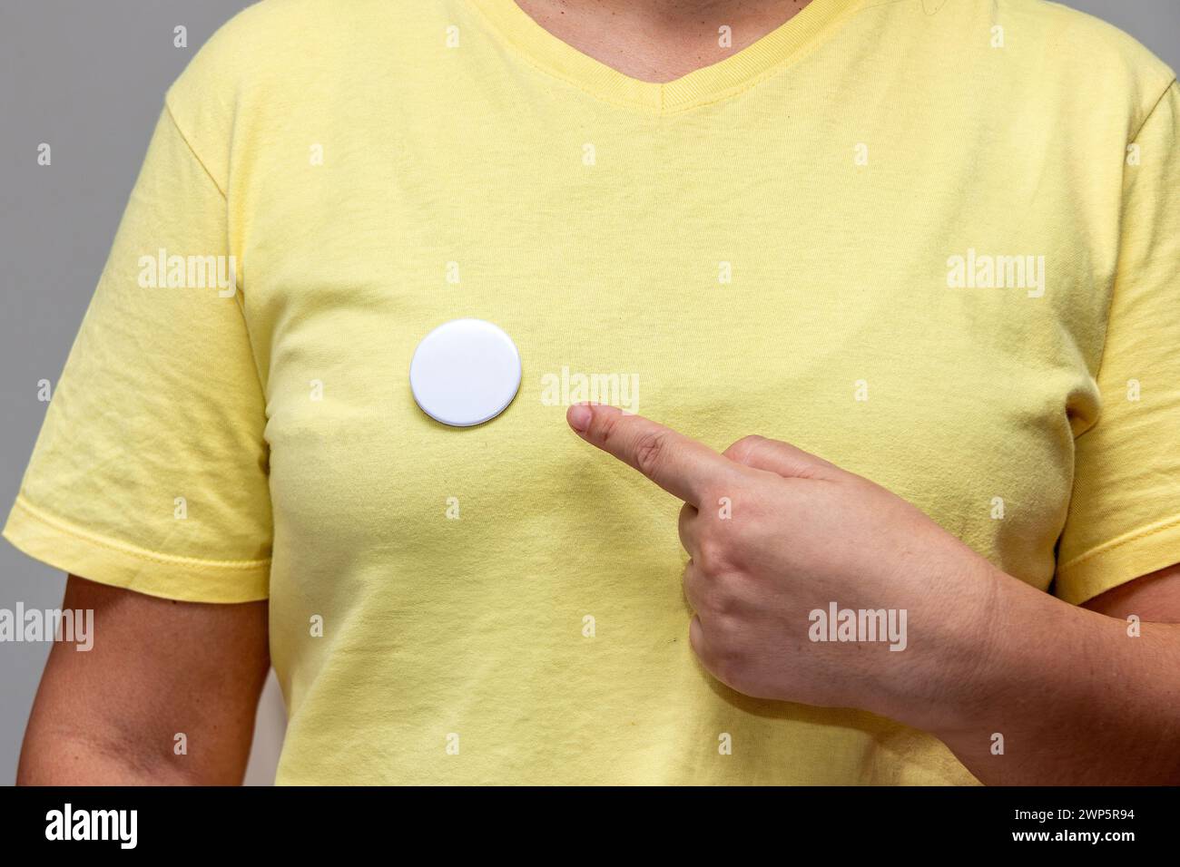 Woman in yellow shirt pointing at a shiny round button. Isolated pin ...