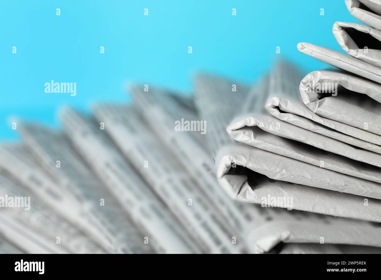Stack of newspapers on light blue background, closeup. Journalist's ...