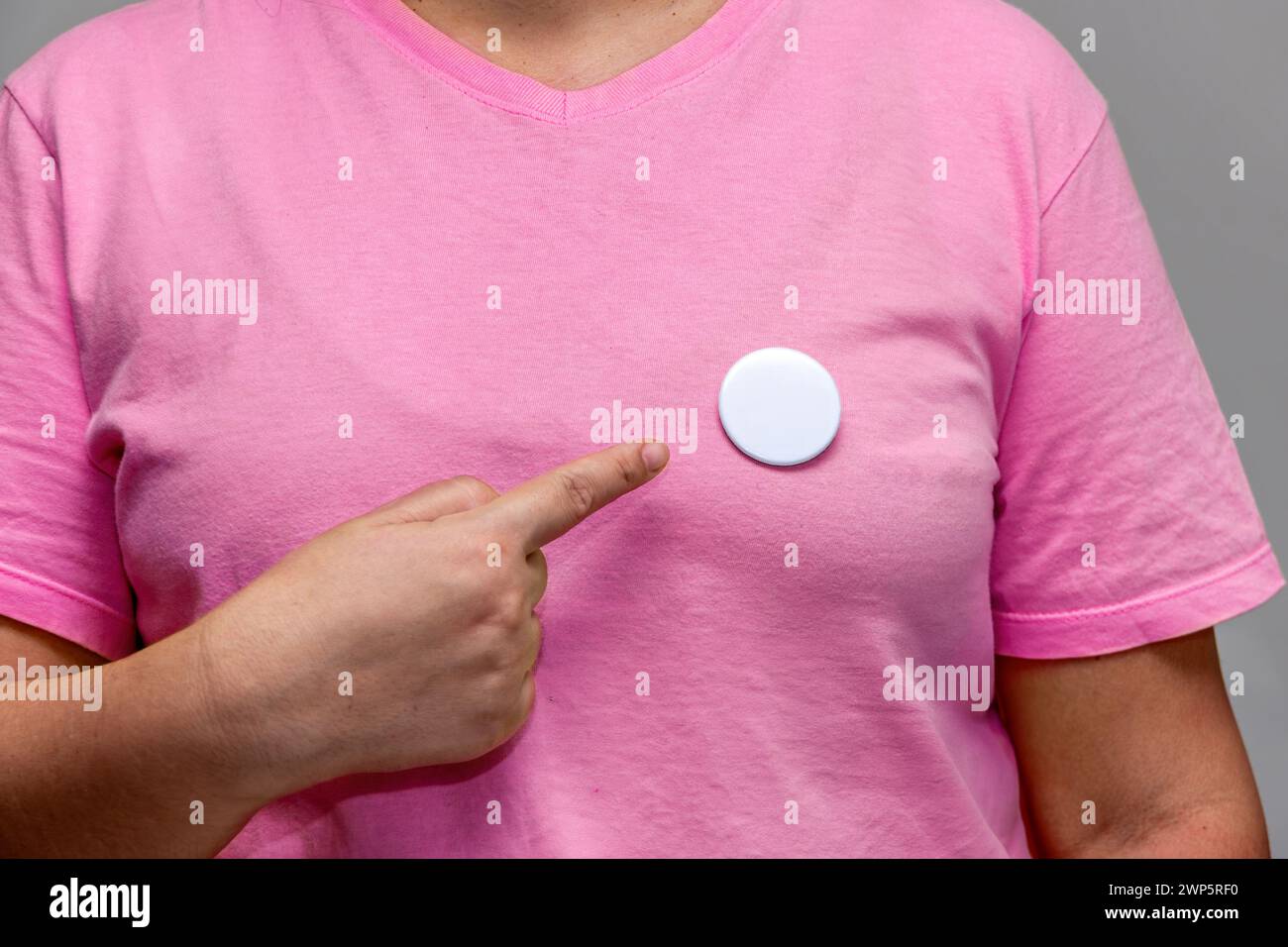 Woman in pink shirt pointing at a shiny round button. Isolated pin ...