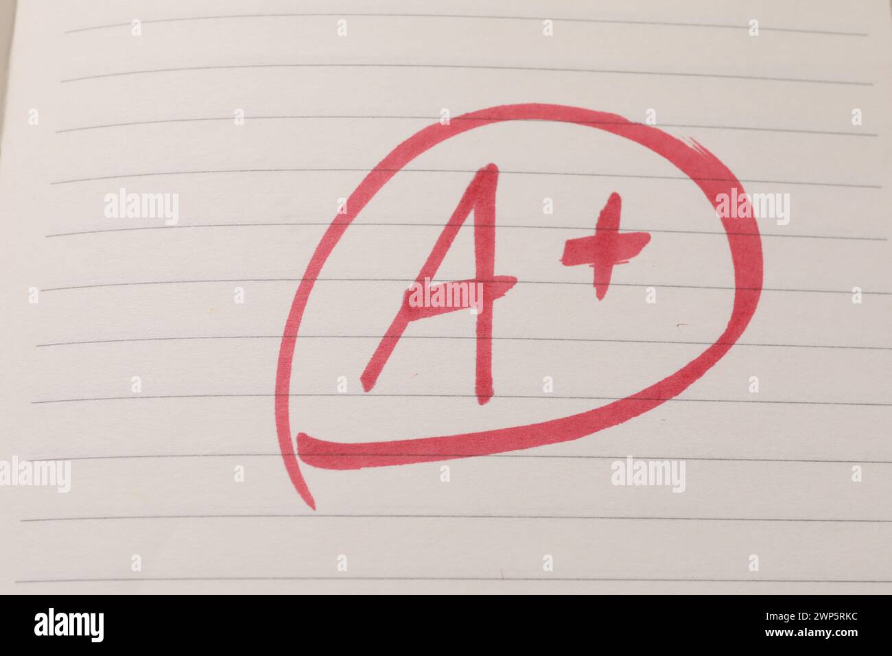 School grade. Red letter A with plus symbol on notebook paper, top view ...