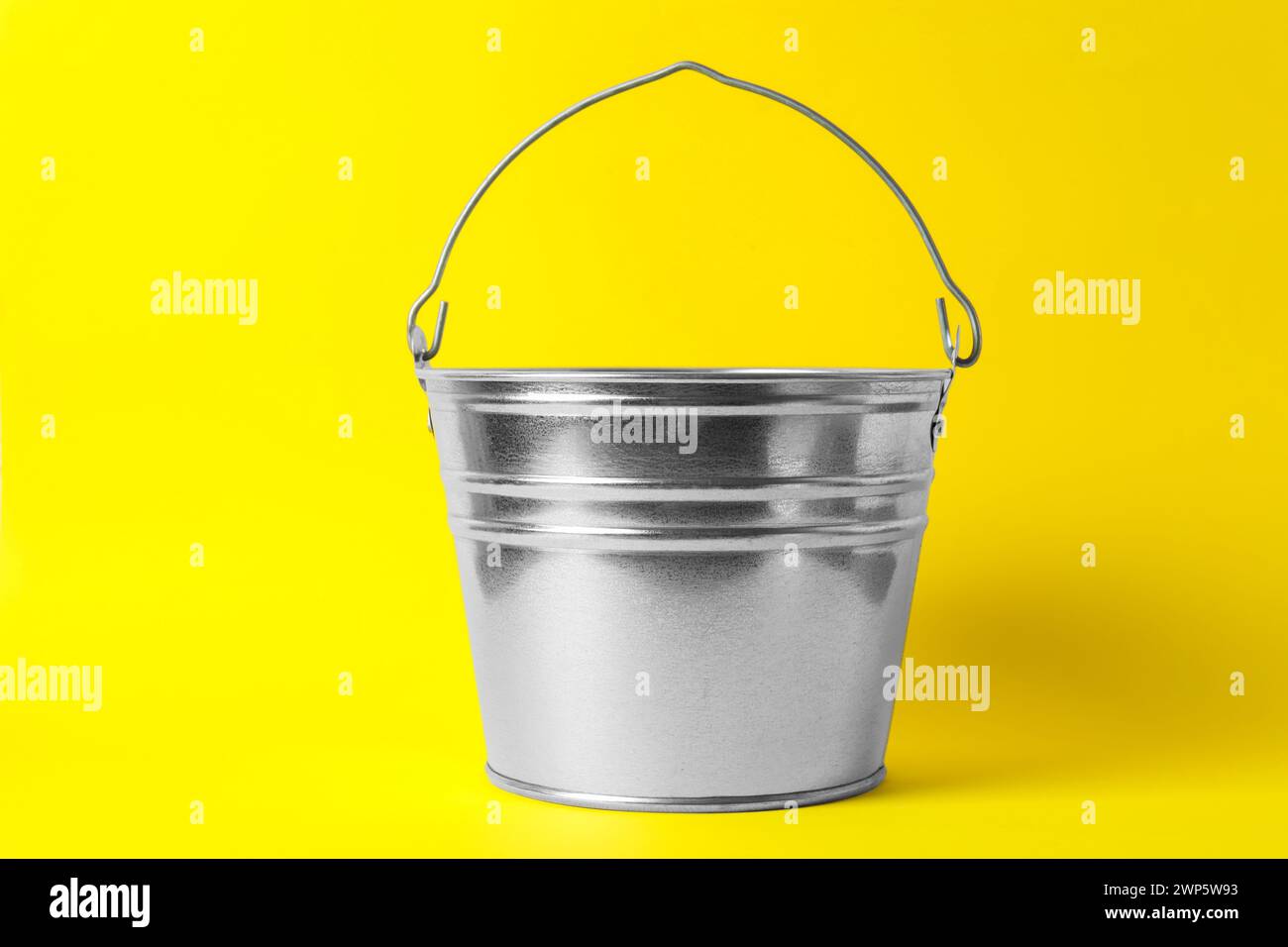 One shiny metal bucket on yellow background Stock Photo - Alamy
