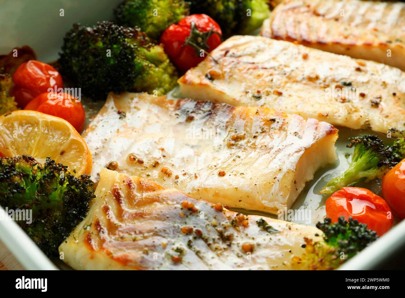 Pieces of delicious baked cod with vegetables and spices in dish ...