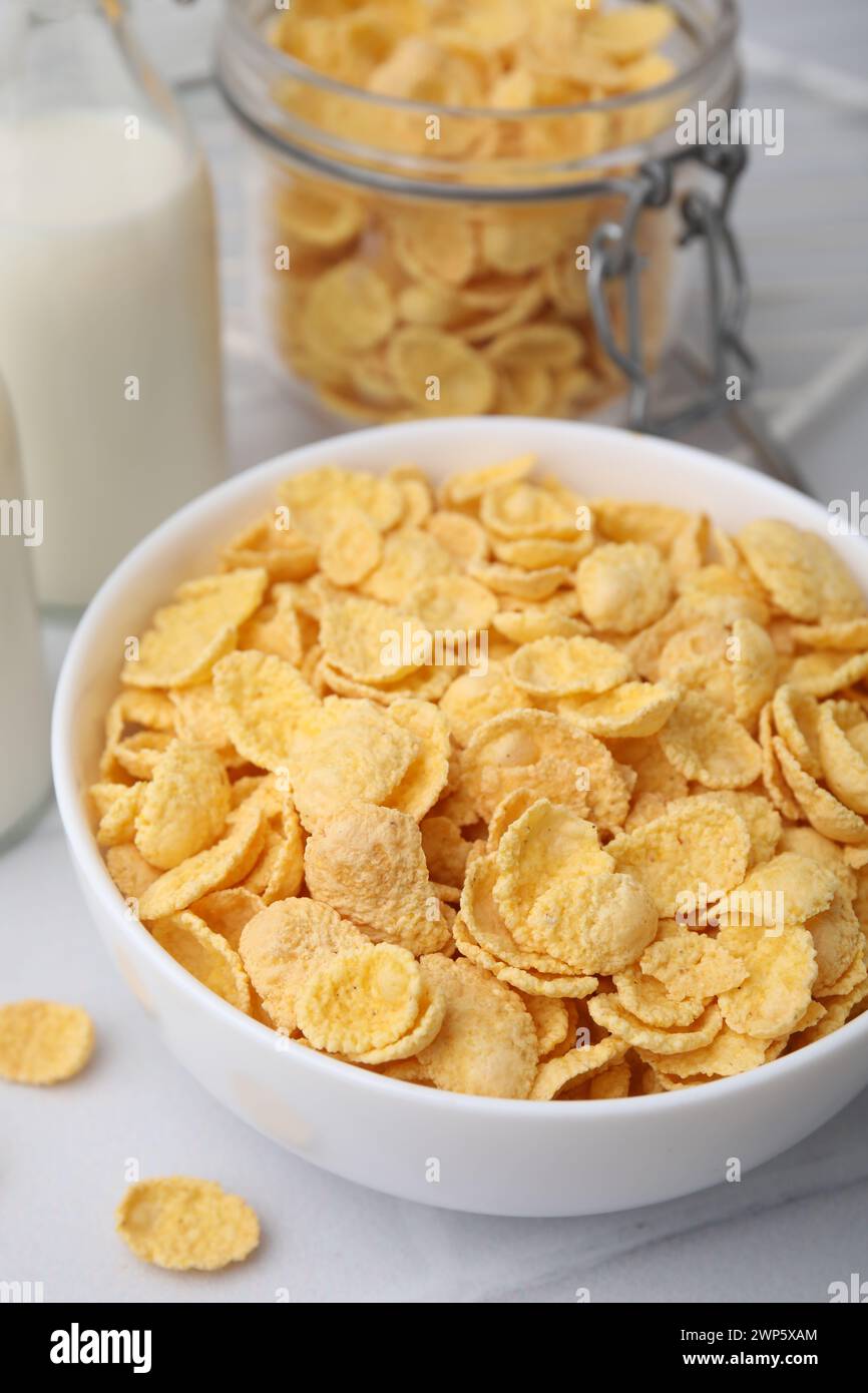 Tasty crispy corn flakes in bowl on white table, closeup. Breakfast ...