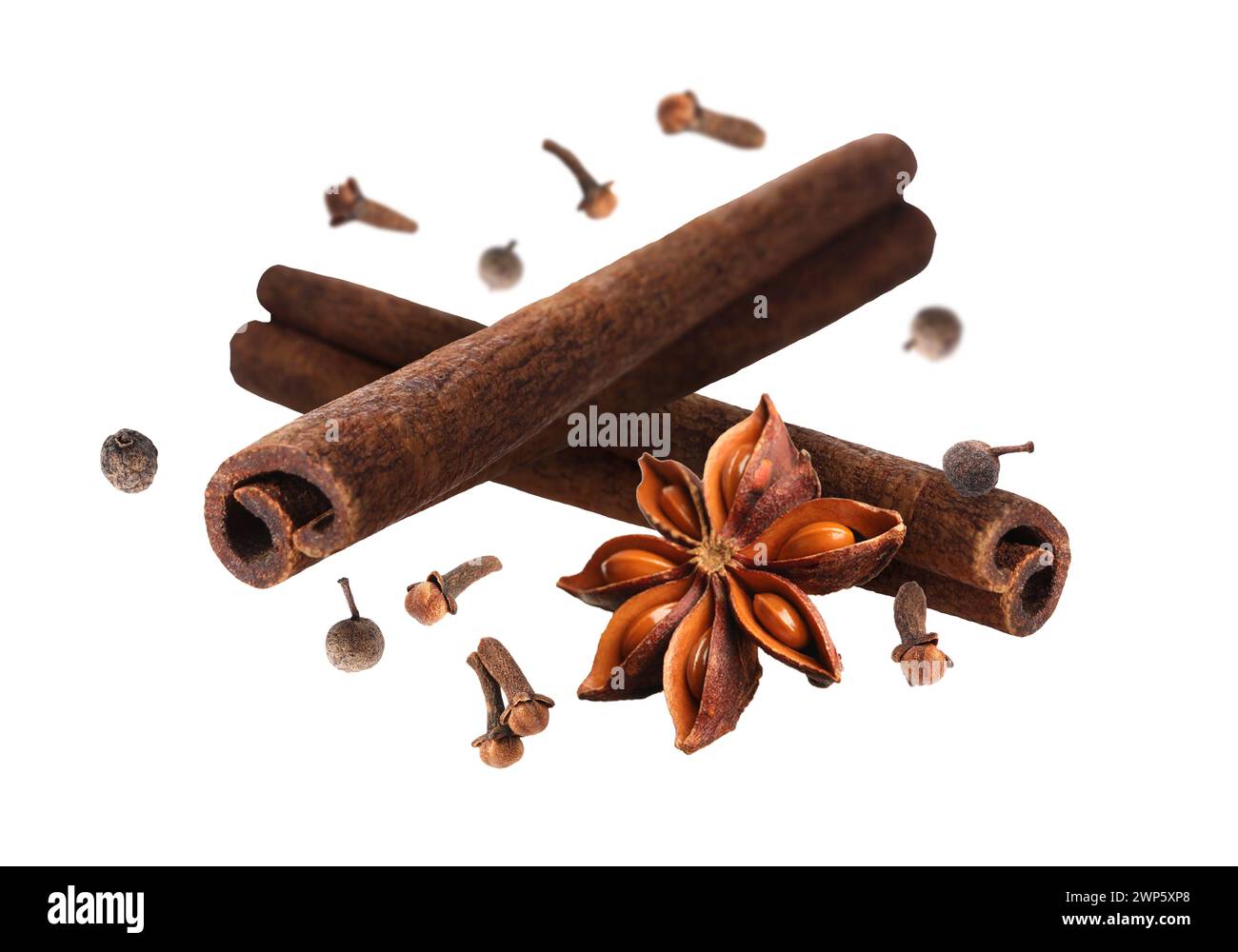 Cinnamon sticks and other aromatic spices falling on white background ...