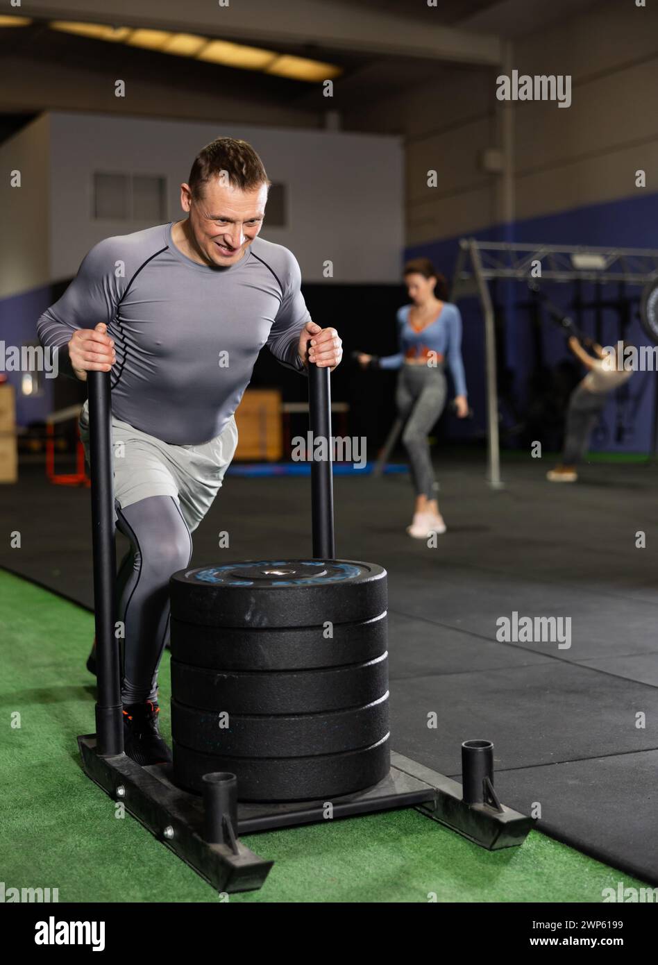 Determined man pushing heavily loaded sled at workout in gym Stock ...