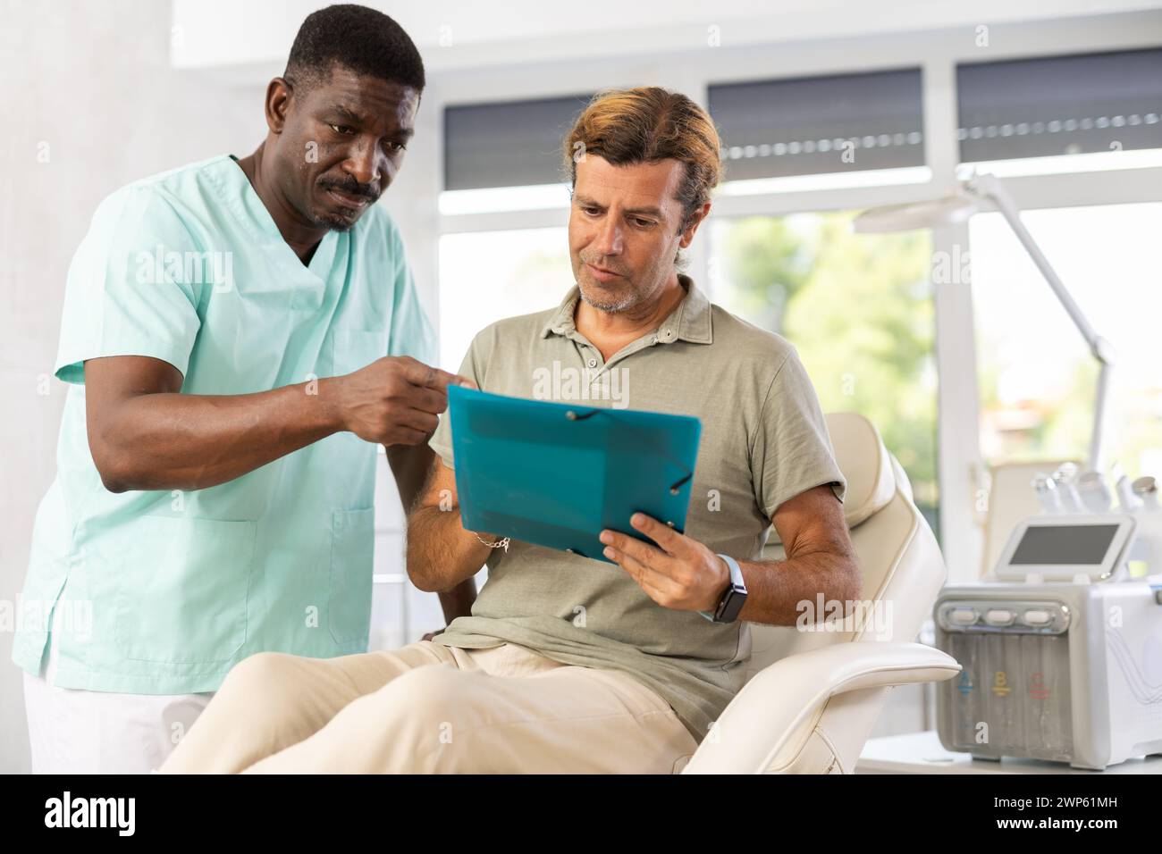 African American esthetician obtaining consent of male patient for ...