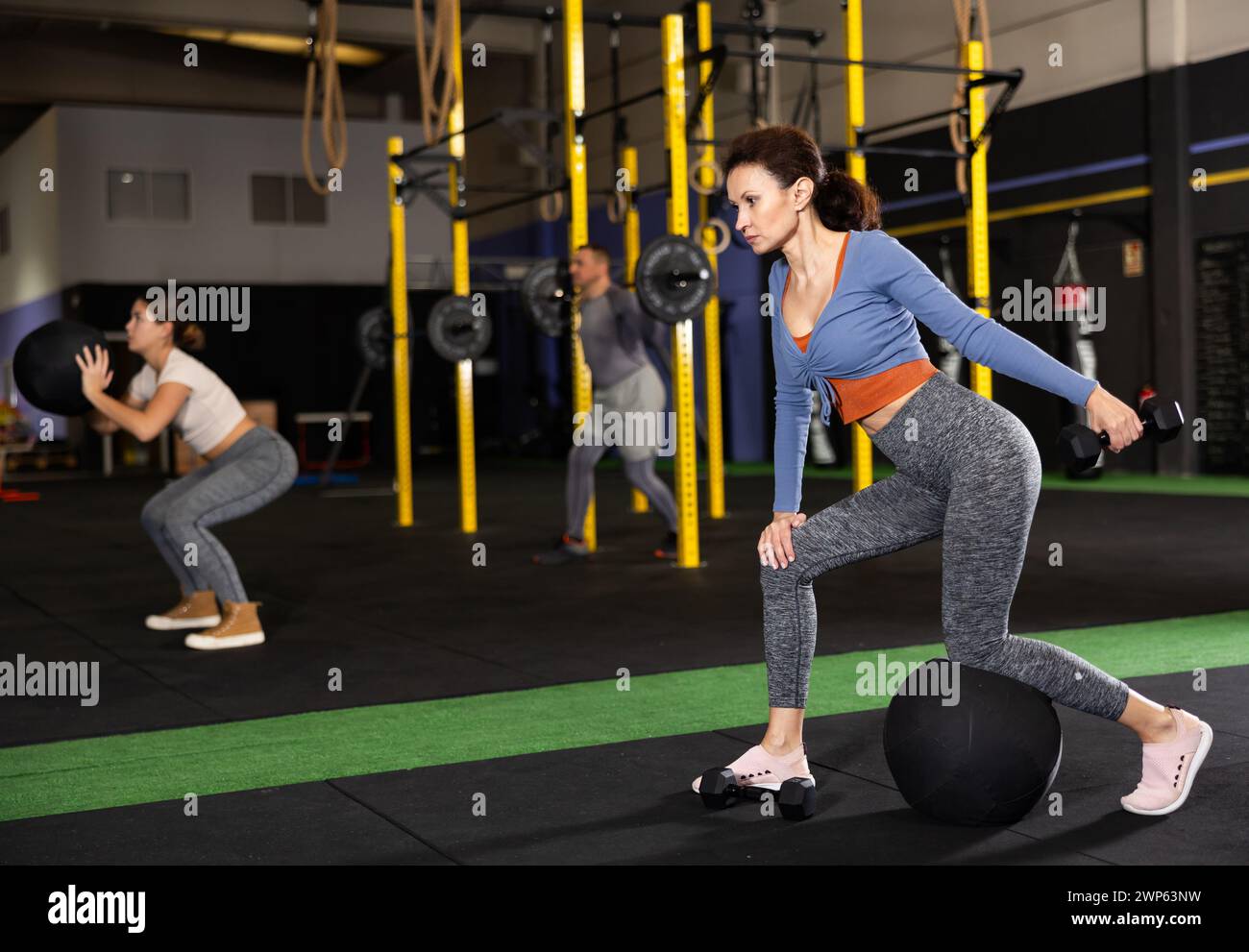 Slender woman trains muscles of arms and back using dumb-bell shaped ...