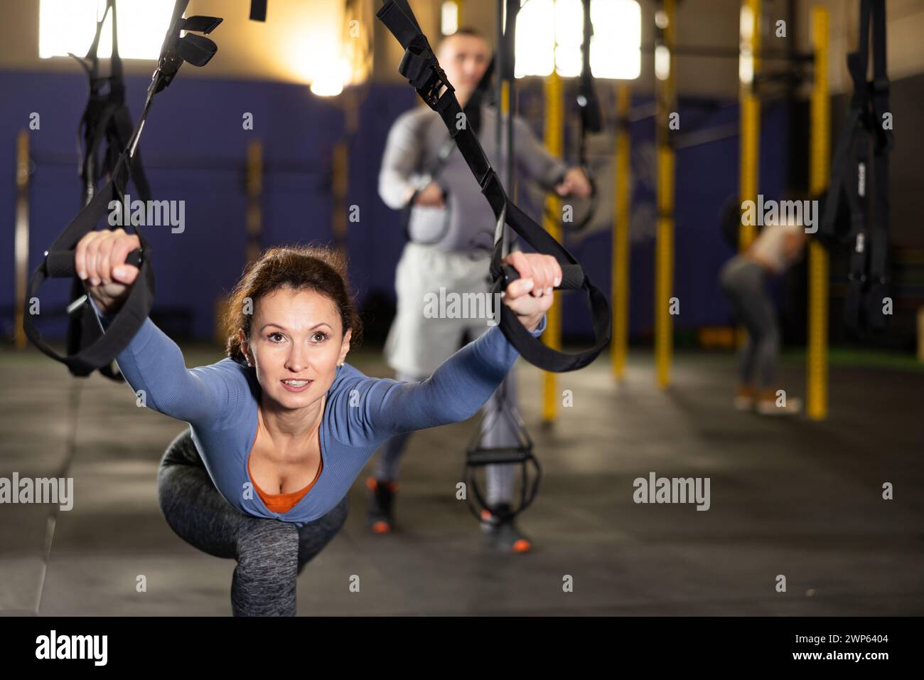 Female athlete with group working out on gymnastics rings at crossfit ...