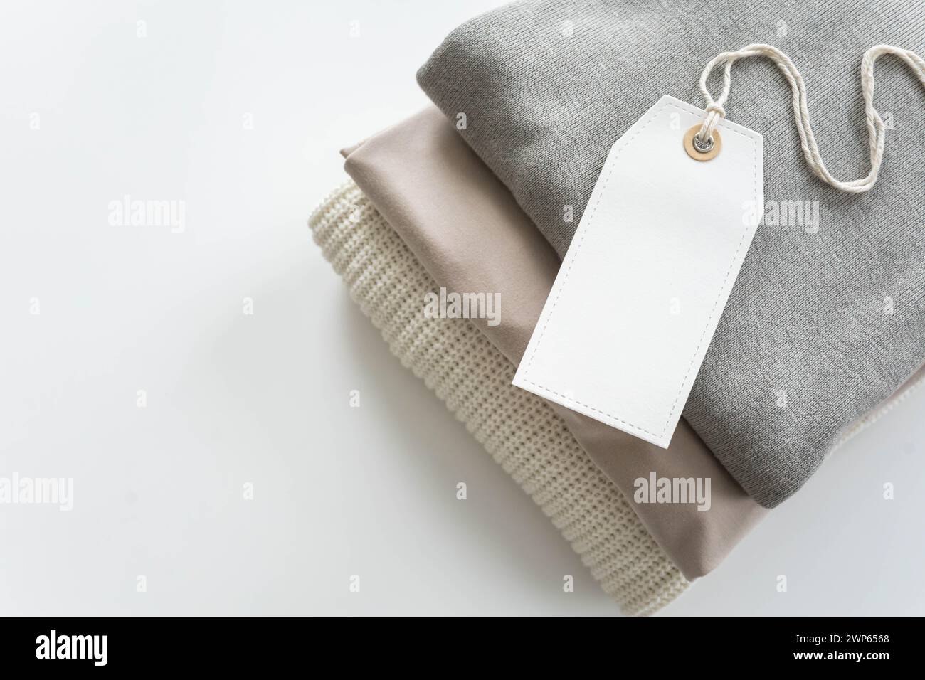 A neat stack of clean knitwear in neutral colors. Blank white label ...