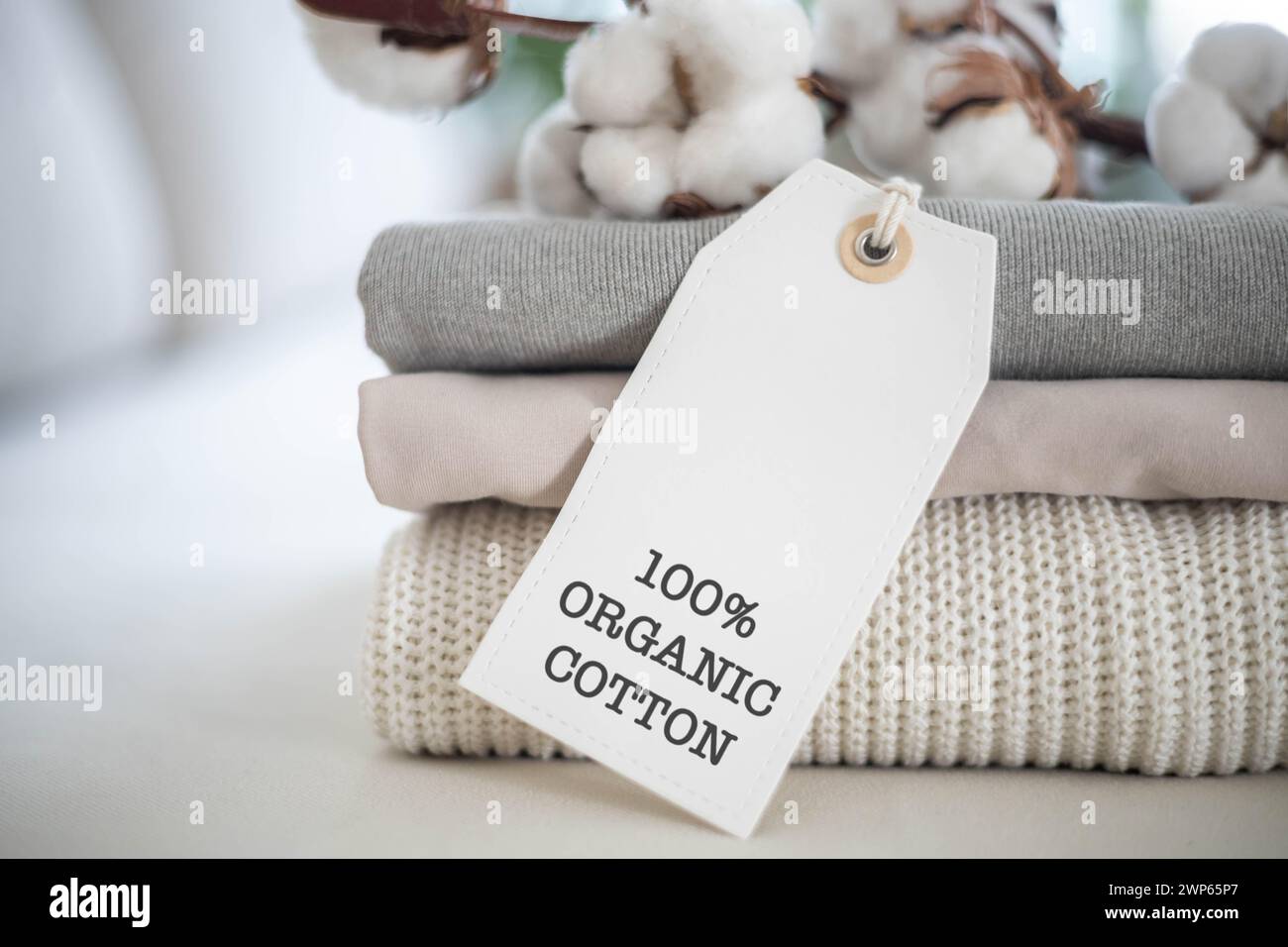 A neat stack of knitted clothing labeled 100% organic cotton. White ...