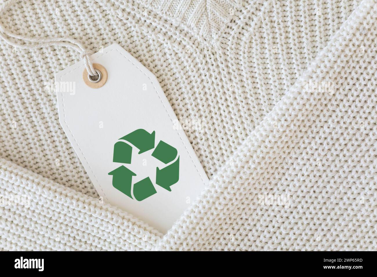 White knitted clothing with a white label featuring the recycling ...